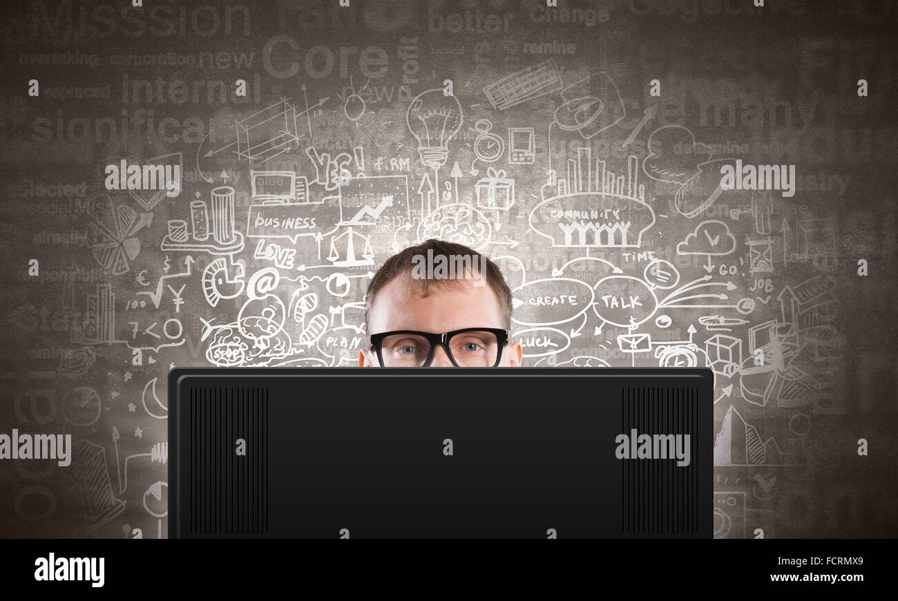 Young man looking out above laptop monitor Stock Photo - Alamy