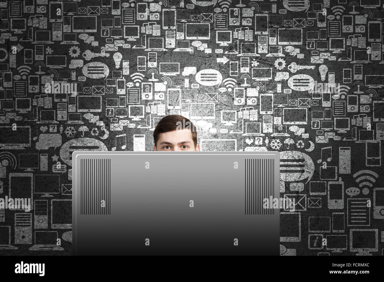 Young man looking out above laptop monitor Stock Photo - Alamy