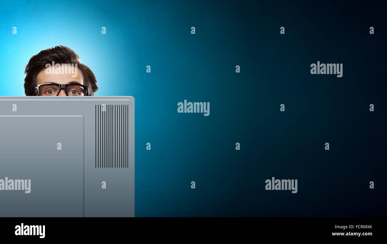 Young man looking out above laptop monitor Stock Photo - Alamy