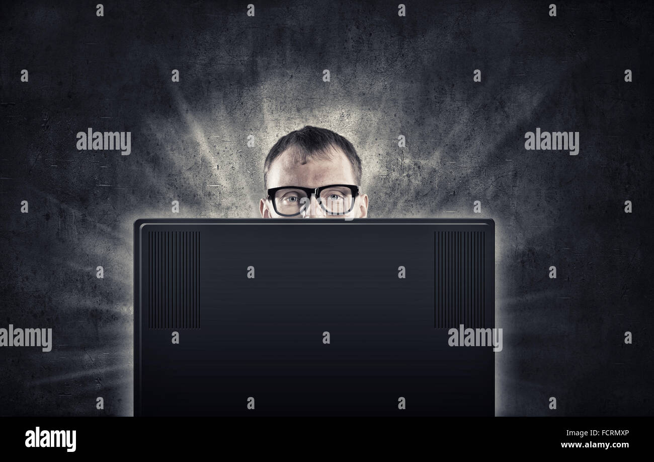Young man looking out above laptop monitor Stock Photo - Alamy