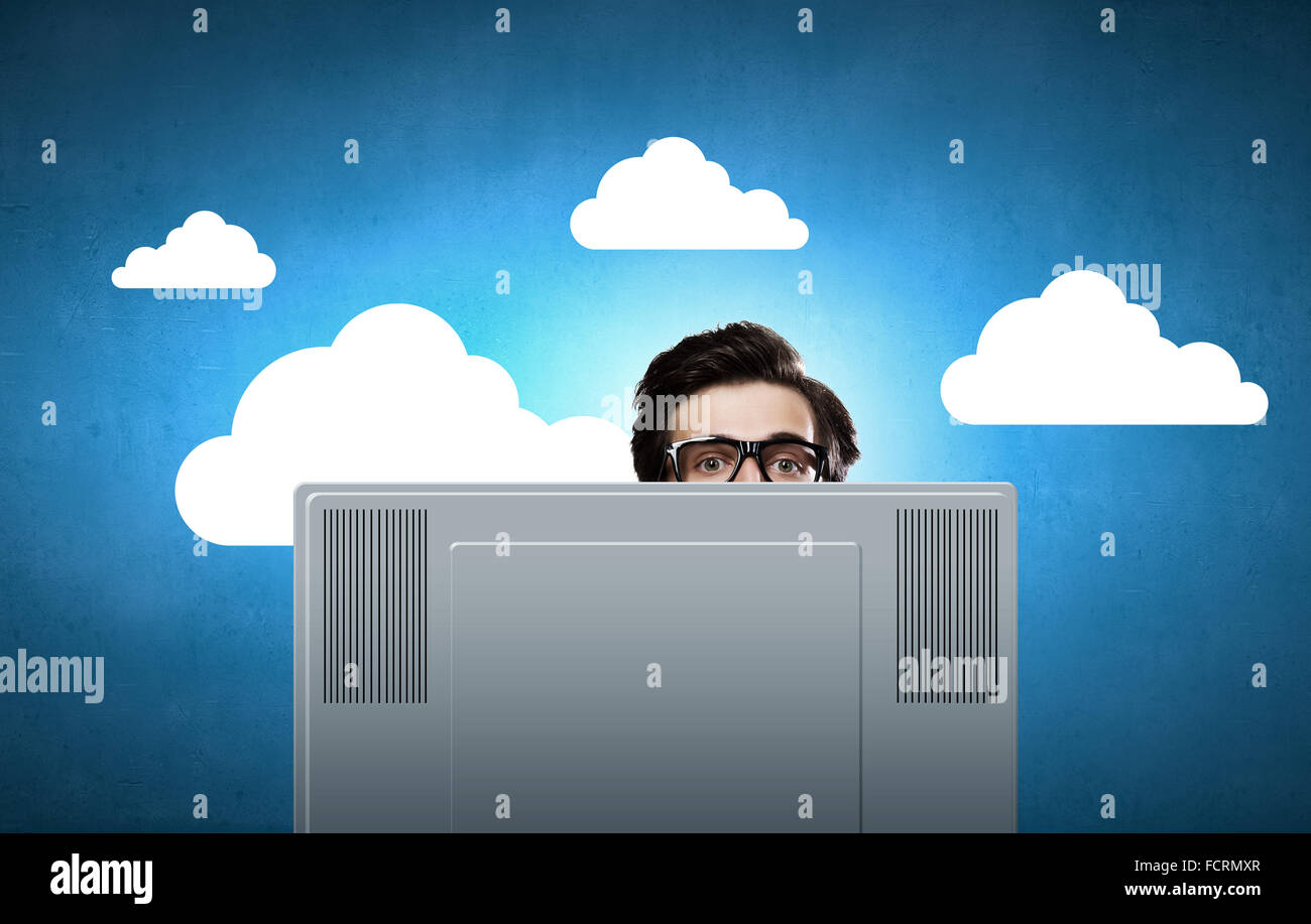 Young man looking out above laptop monitor Stock Photo - Alamy