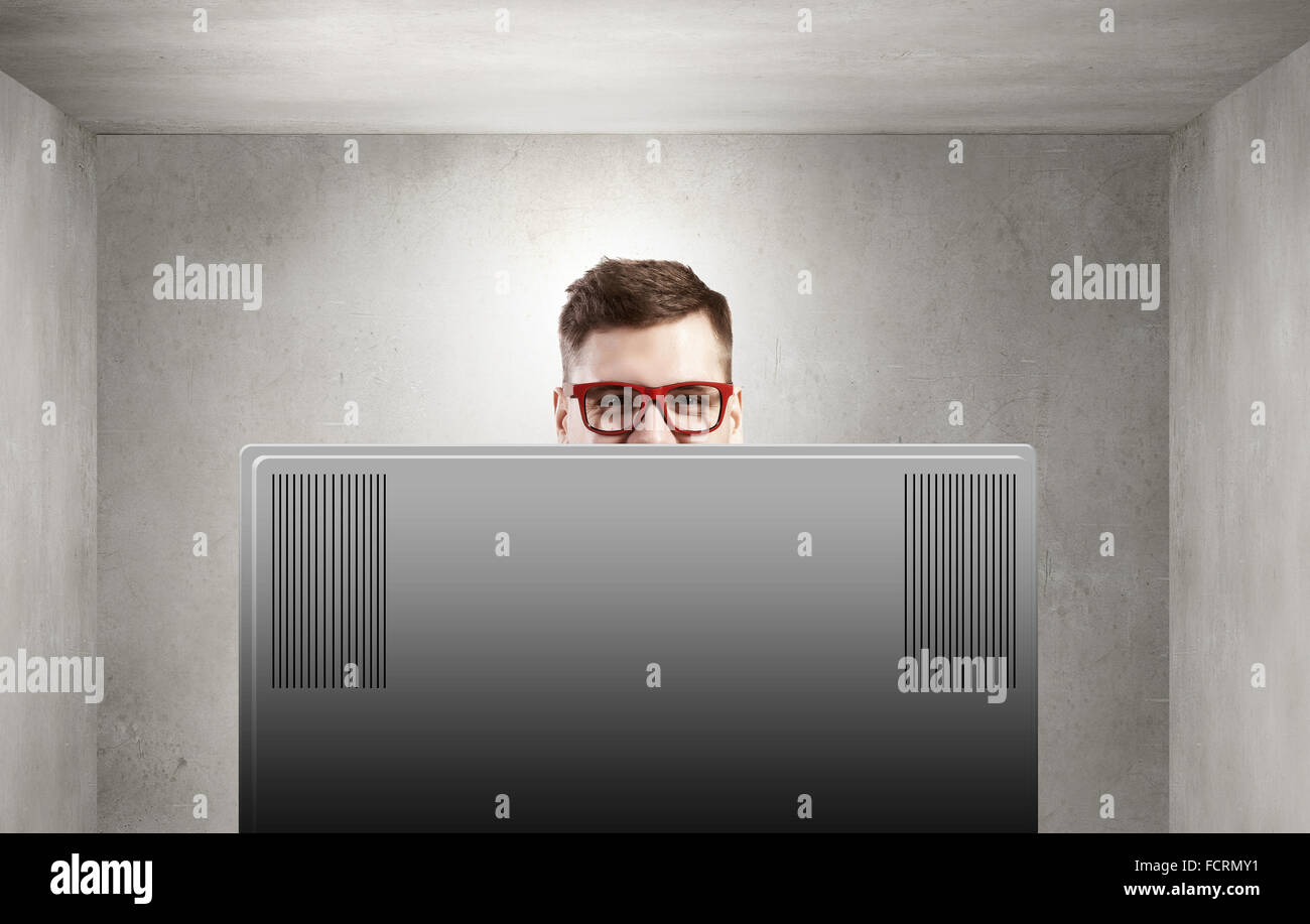 Young man looking out above laptop monitor Stock Photo - Alamy