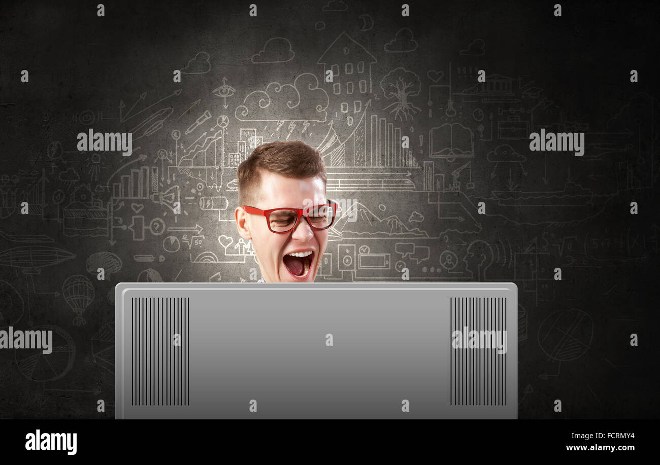 Young man looking out above laptop monitor Stock Photo - Alamy