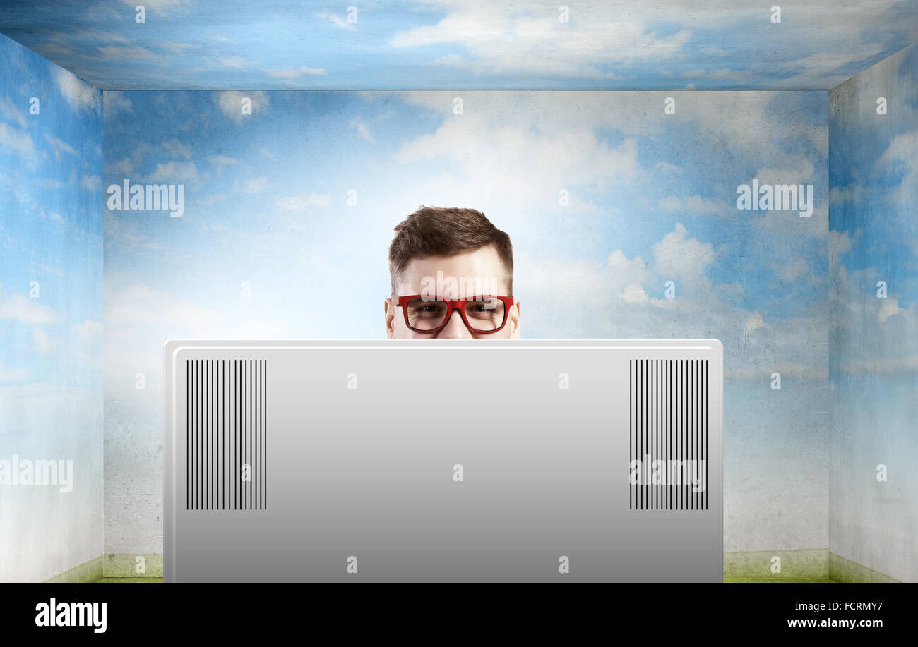 Young man looking out above laptop monitor Stock Photo - Alamy