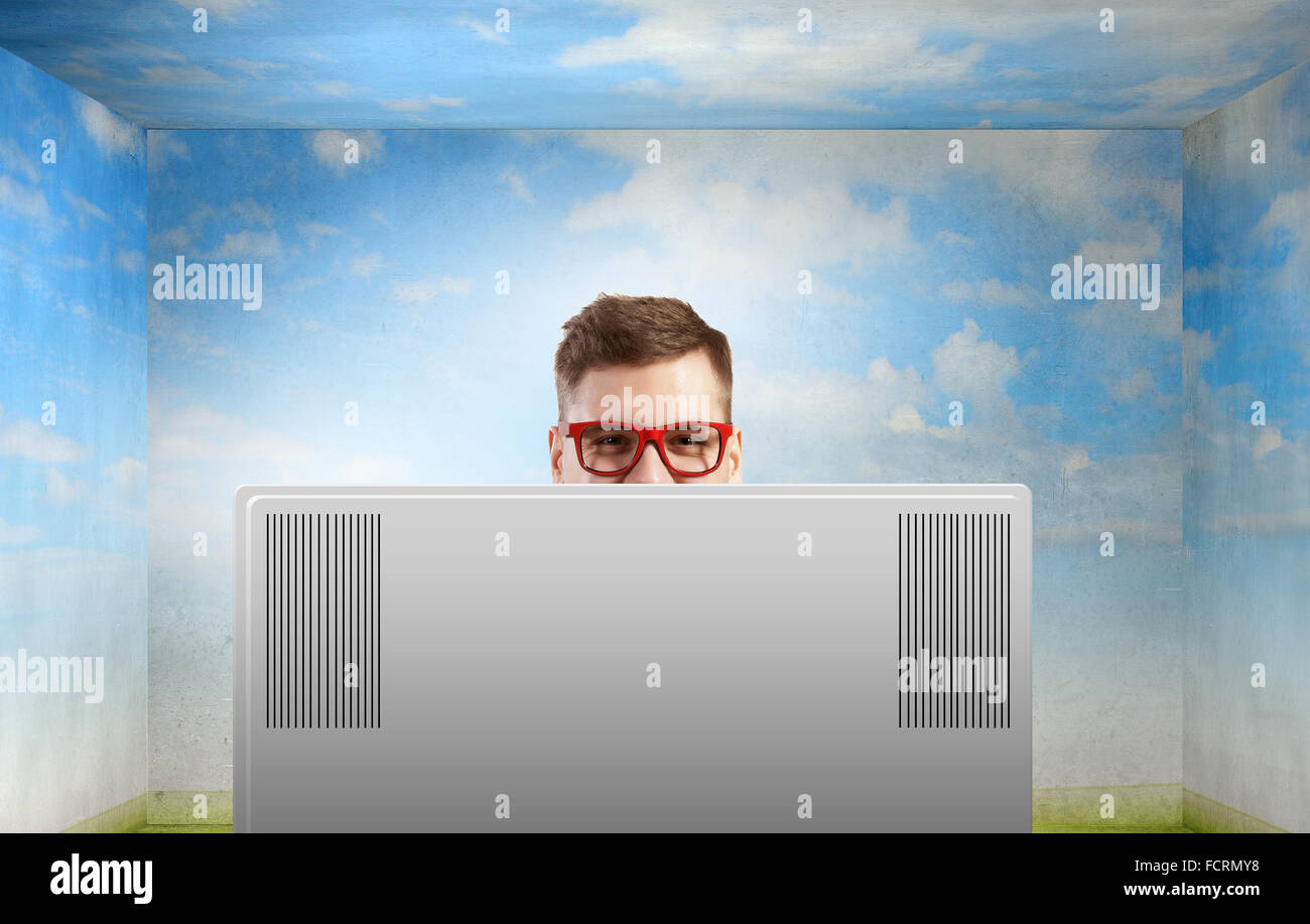 Young man looking out above laptop monitor Stock Photo - Alamy