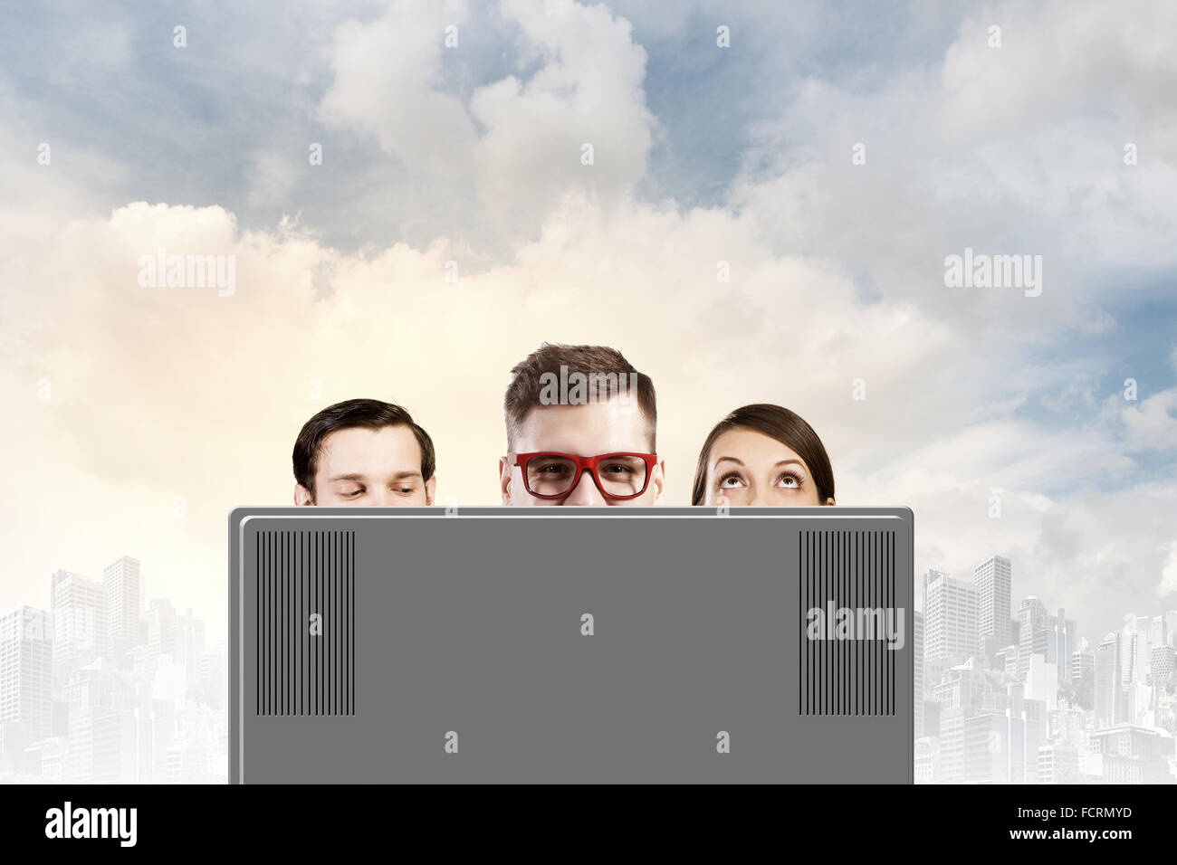 Young people looking out above laptop monitor Stock Photo - Alamy