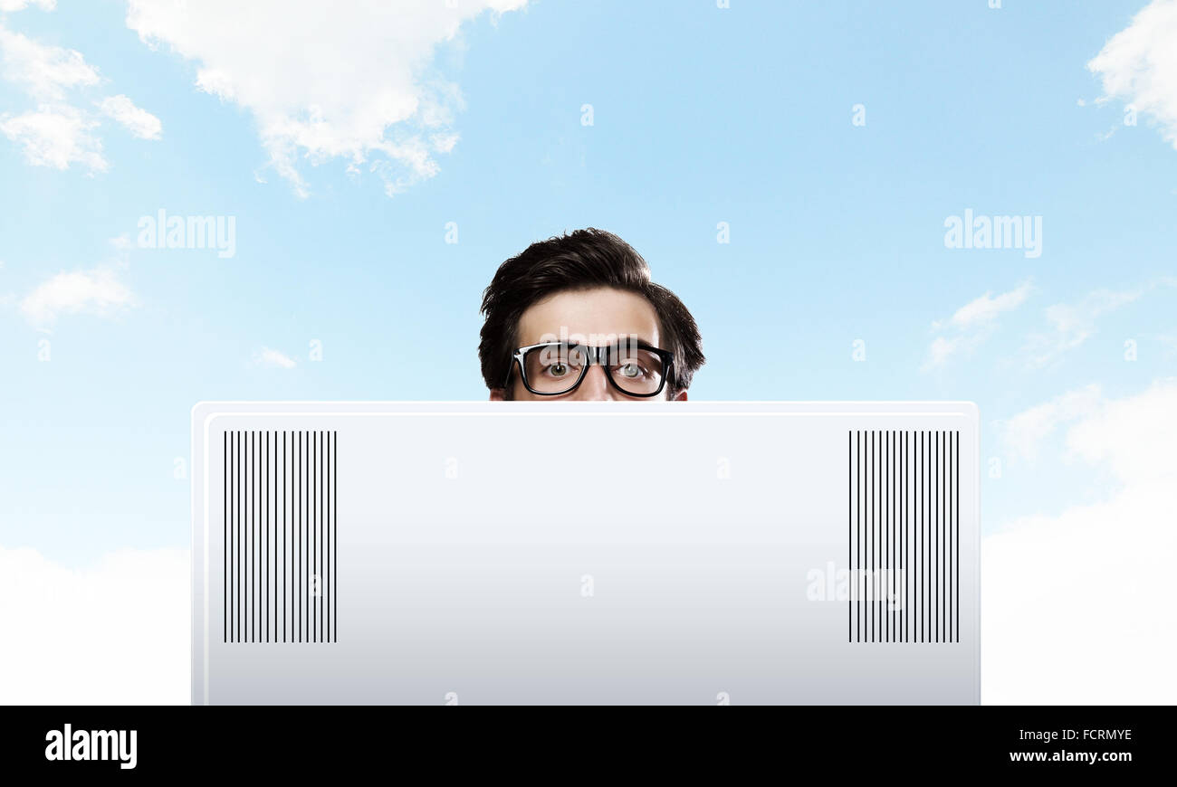 Young man looking out above laptop monitor Stock Photo - Alamy