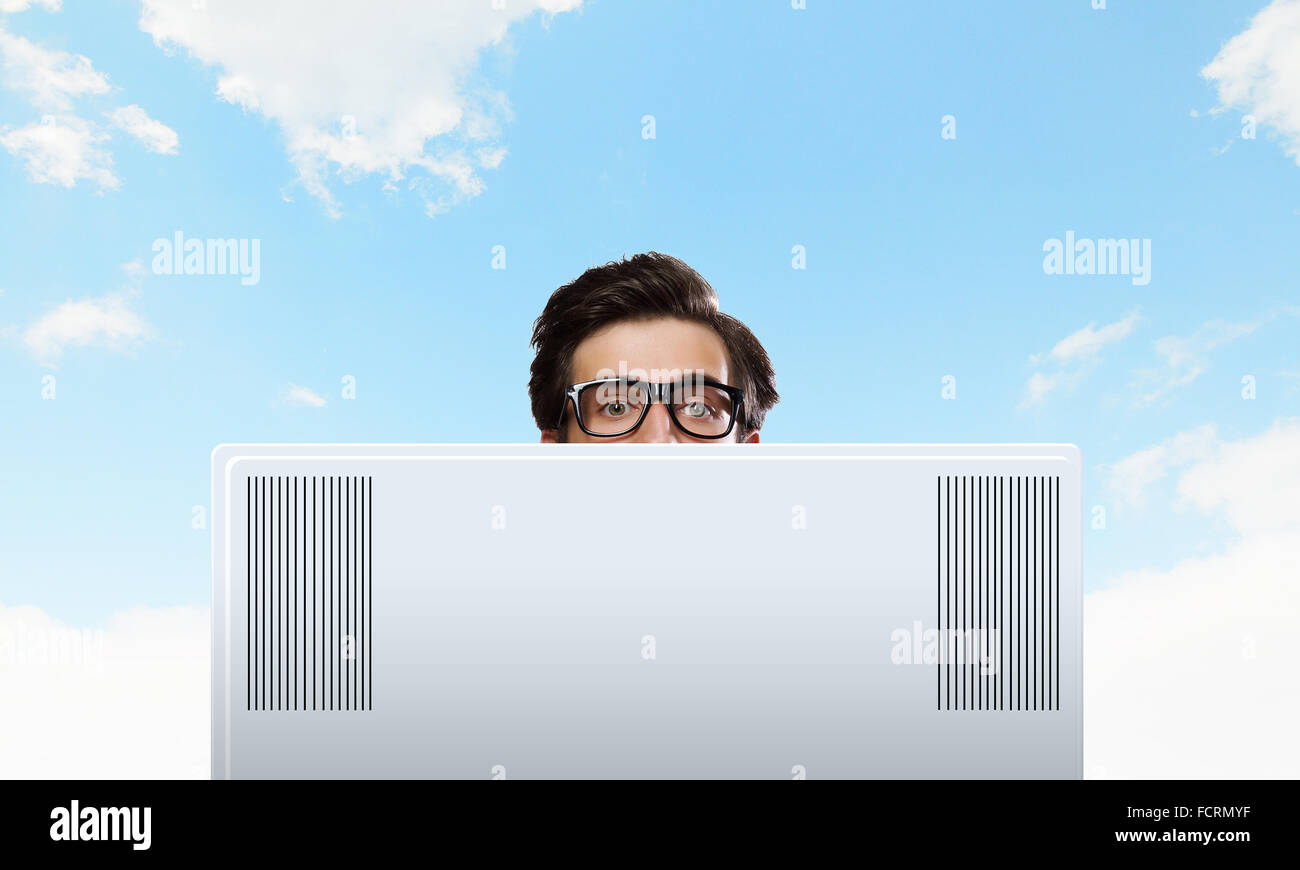 Young man looking out above laptop monitor Stock Photo - Alamy