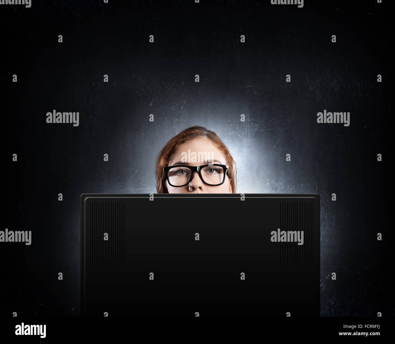 Young woman looking out above laptop monitor Stock Photo - Alamy