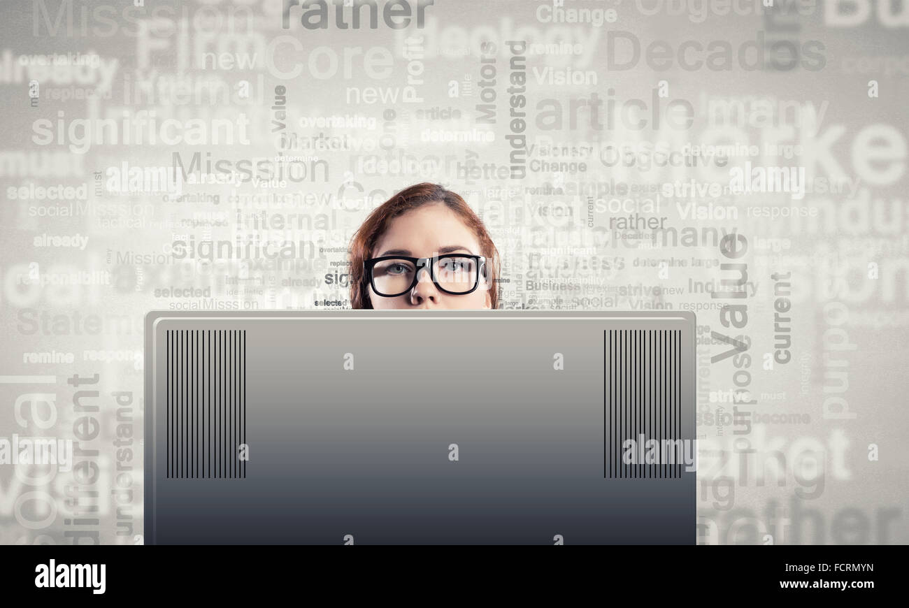 Young woman looking out above laptop monitor Stock Photo - Alamy