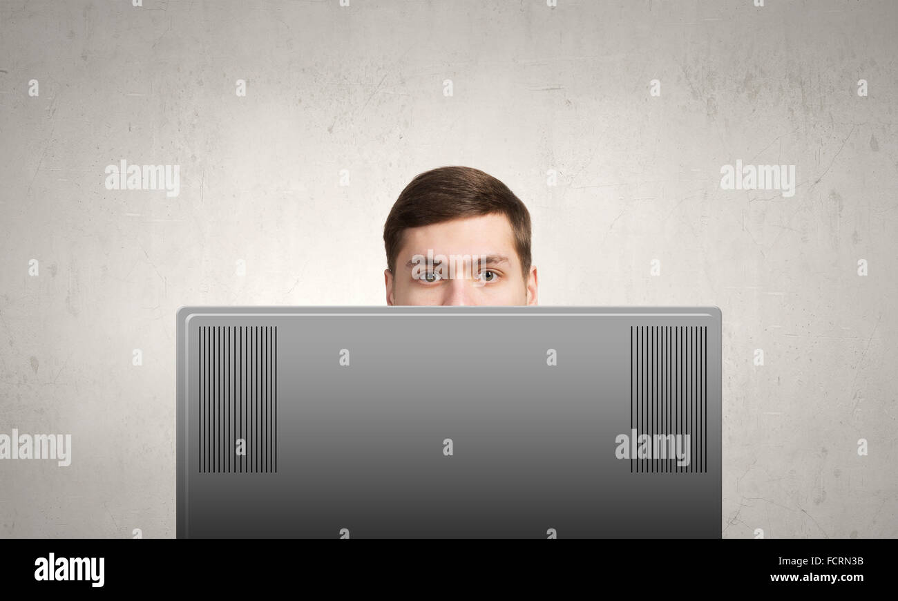 Young man looking out above laptop monitor Stock Photo - Alamy