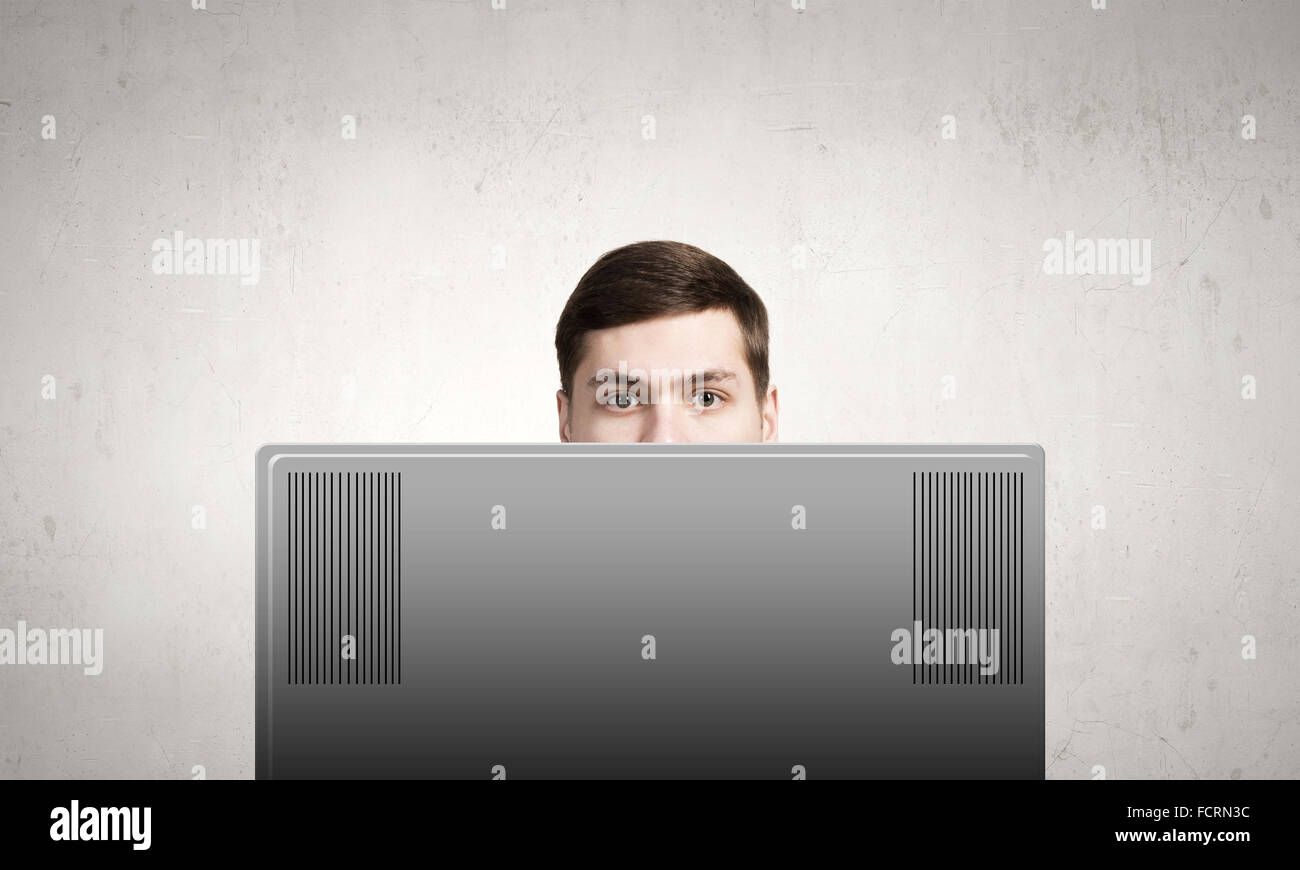 Young man looking out above laptop monitor Stock Photo - Alamy