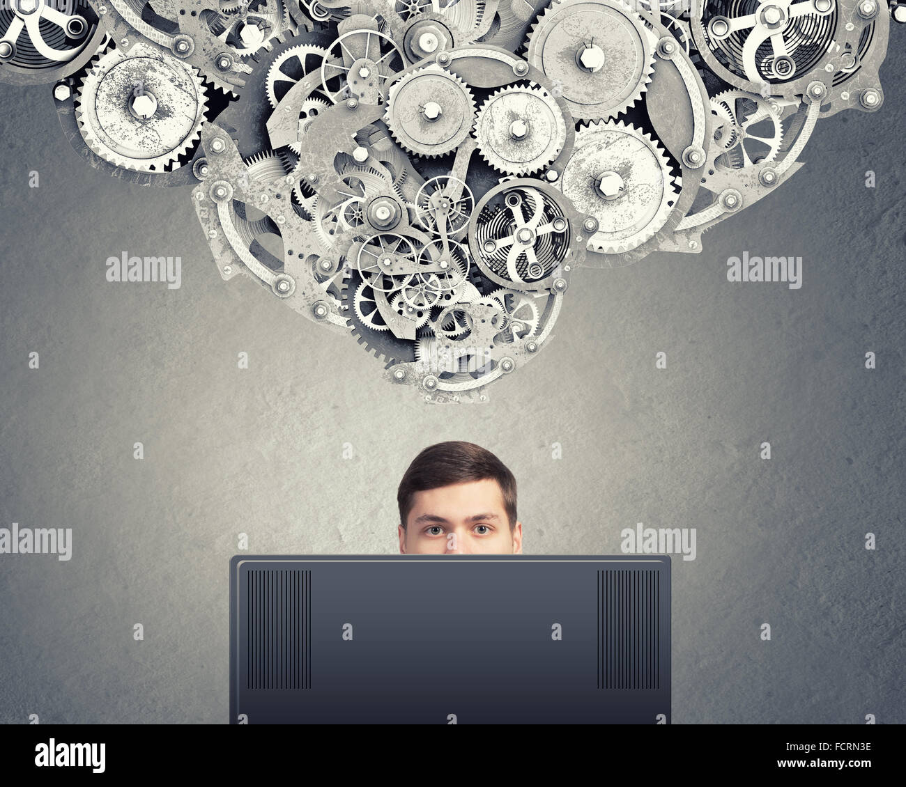 Young man looking out above laptop monitor Stock Photo - Alamy