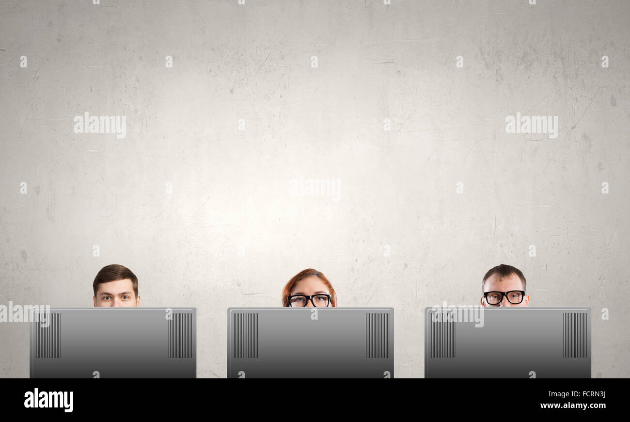 Young people looking out above laptop monitor Stock Photo - Alamy