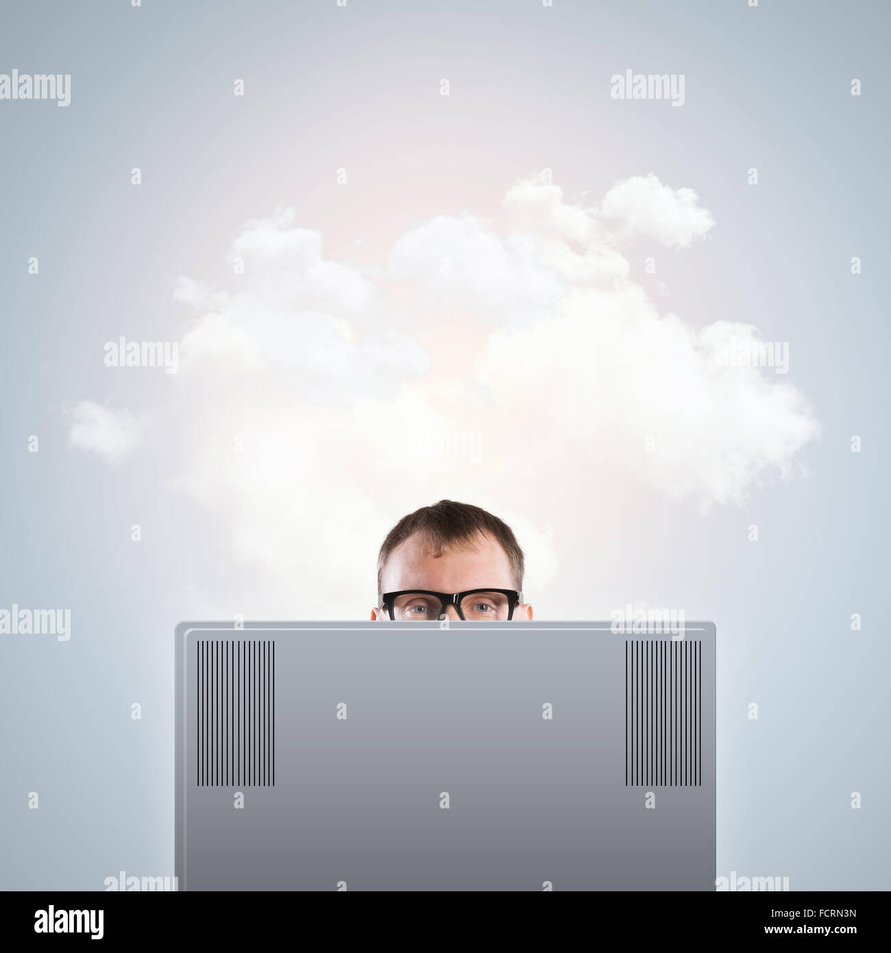 Young man looking out above laptop monitor Stock Photo - Alamy
