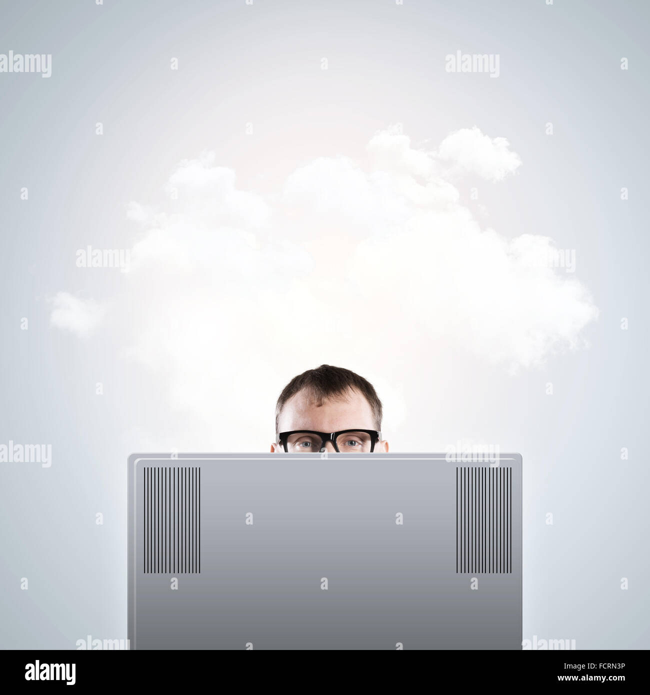 Young man looking out above laptop monitor Stock Photo - Alamy