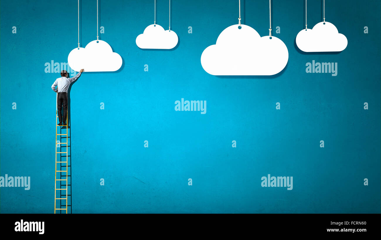 Rear view of businessman standing on ladder and reaching cloud Stock ...