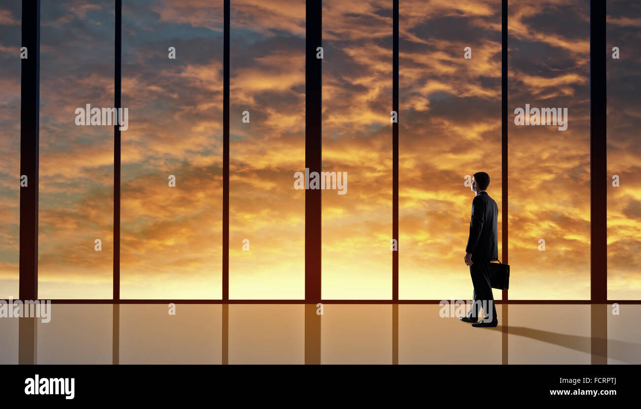 Businessman standing with back and looking in office window Stock Photo ...