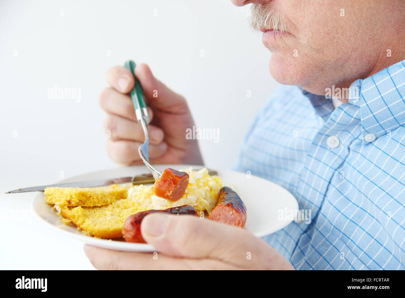 A man eating sausage, scrambled eggs and cornbread for breakfast Stock ...