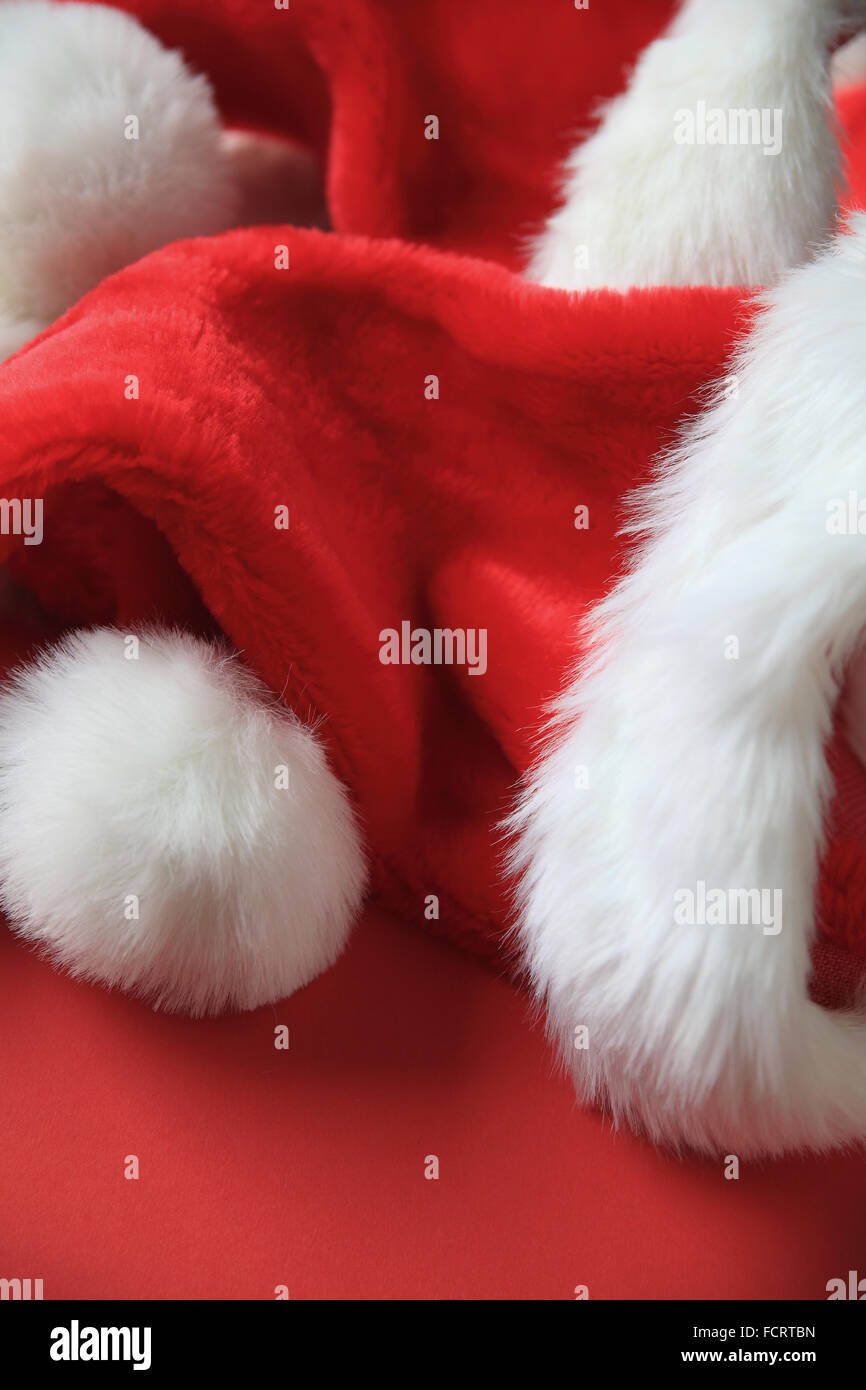 Several furry Santa Claus hats on a red background with copy space ...