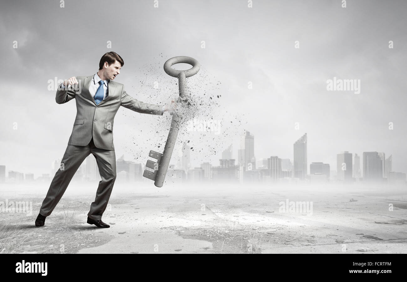 Angry businessman crashing stone key with punch Stock Photo - Alamy