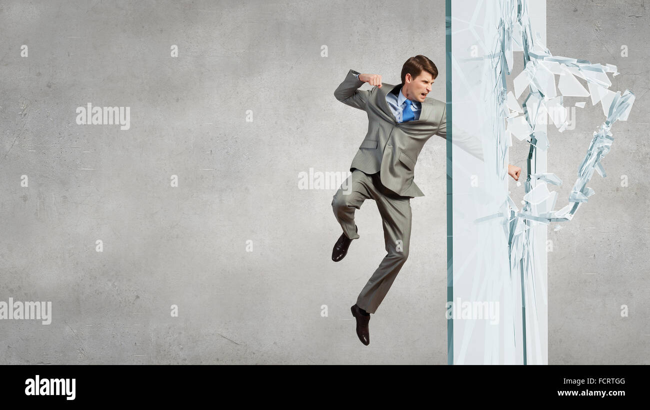 Young determined businessman breaking glass with karate punch Stock ...