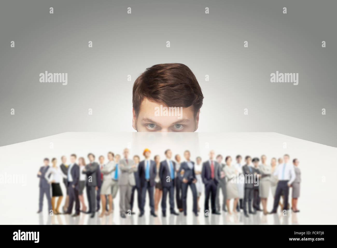 Young man looking from under table on large group of business people ...