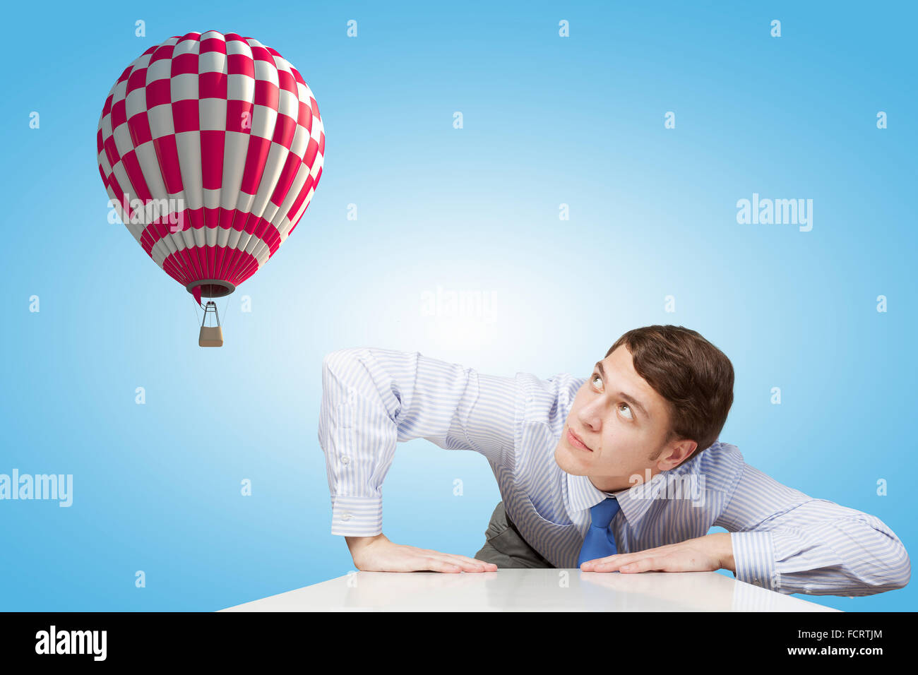 Young man looking from under table on flying balloon Stock Photo - Alamy