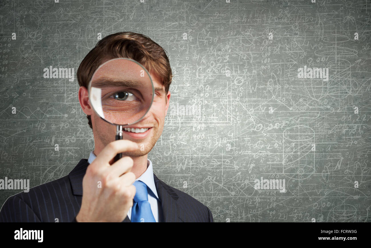 Young smiling man looking in magnifying glass Stock Photo - Alamy