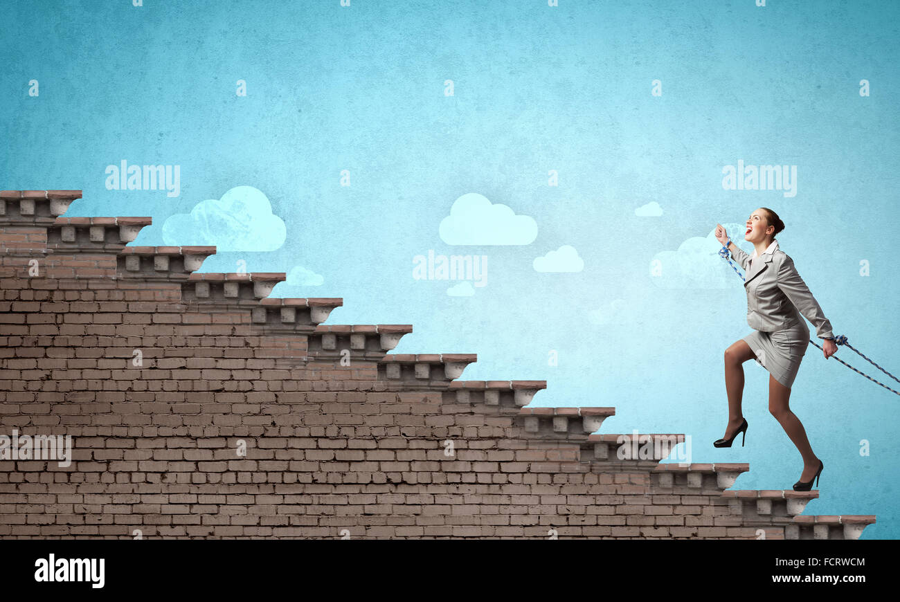 Young businesswoman with ropes on hands climbing ladder Stock Photo - Alamy