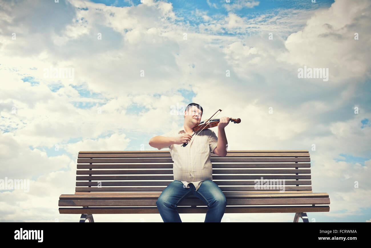 Fat man sitting on bench and playing violin Stock Photo - Alamy