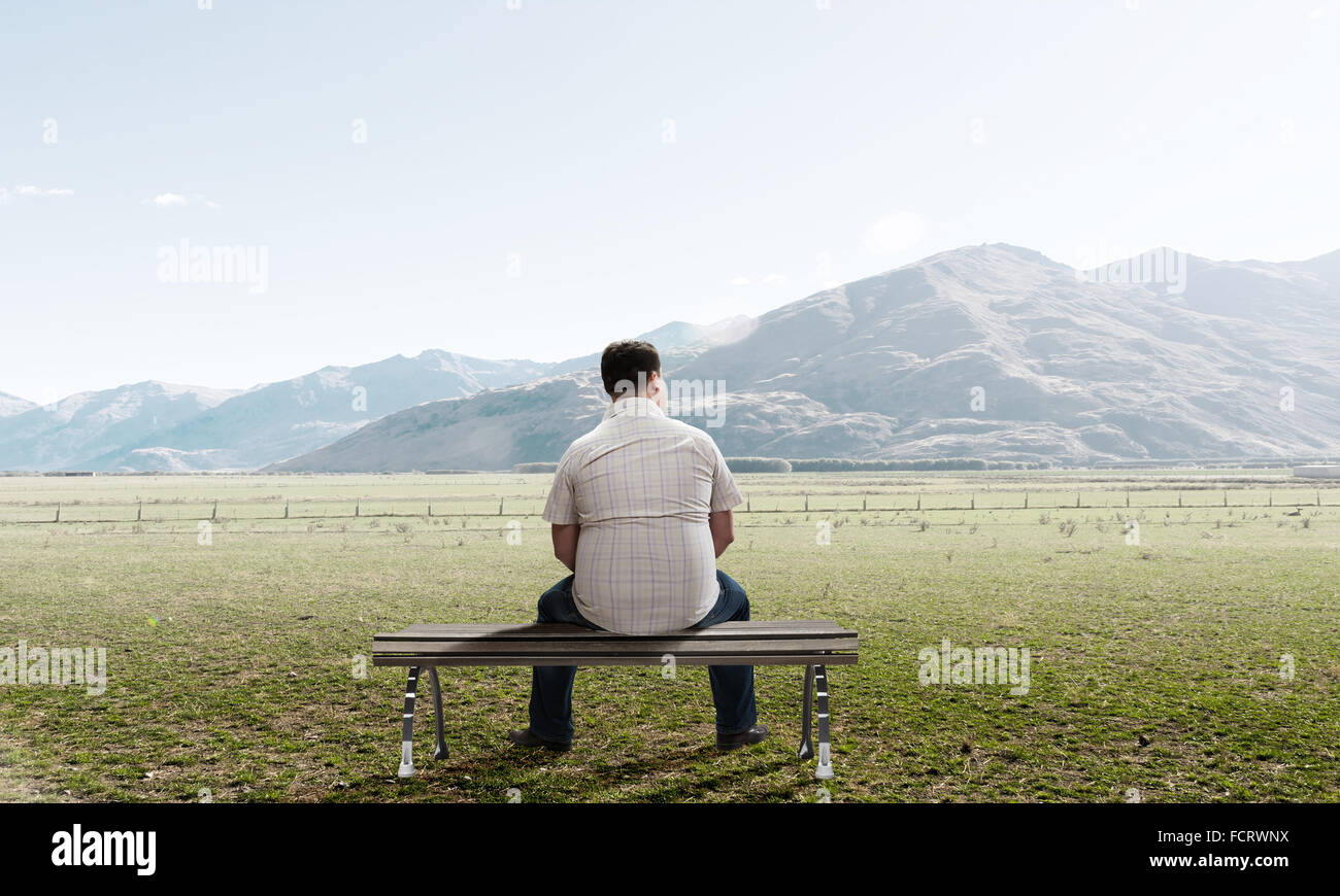 Fat man sitting on bench with his back and looking away Stock Photo - Alamy