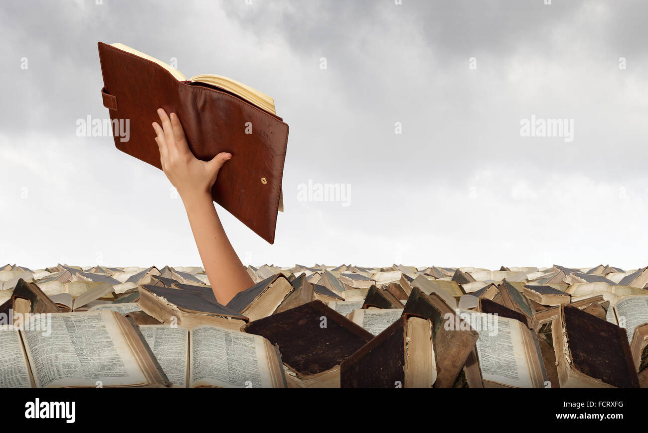 Hand with book reaching out from pile of old books Stock Photo - Alamy