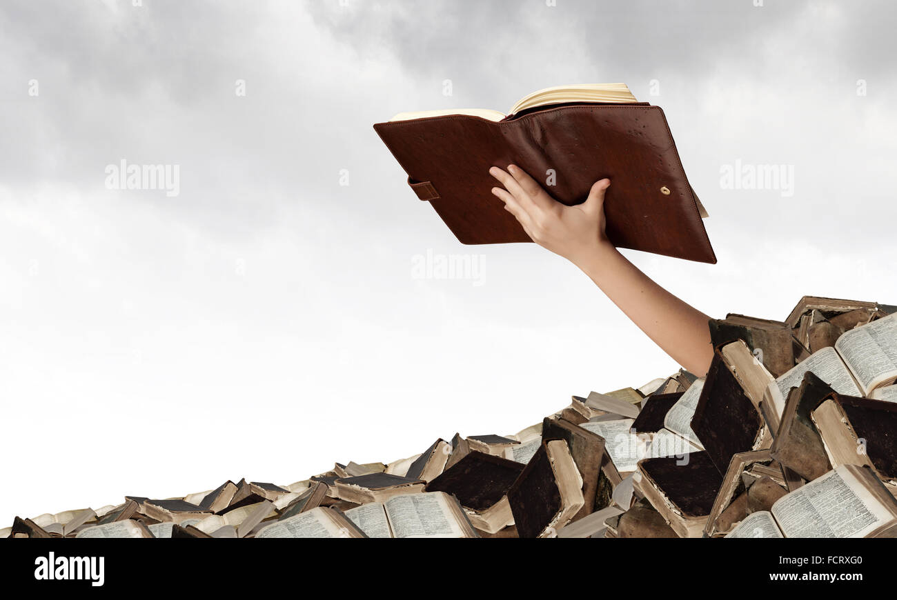Hand with book reaching out from pile of old books Stock Photo - Alamy