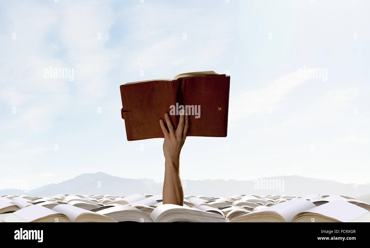 Hand with book reaching out from pile of old books Stock Photo - Alamy