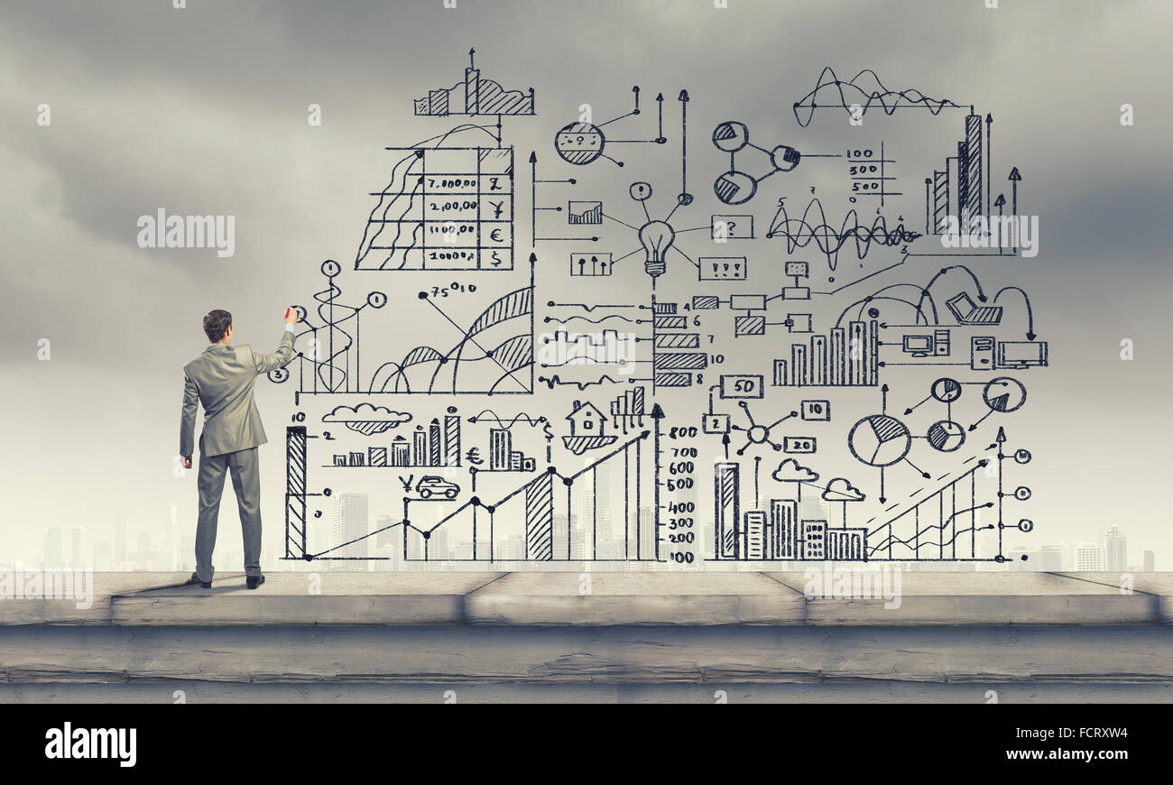 Back view of businessman drawing business sketches on wall Stock Photo ...