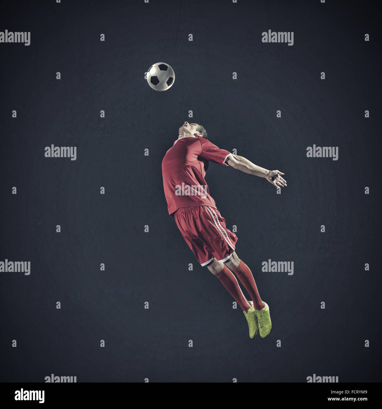 Handsome male football player jumping to hit the ball Stock Photo - Alamy