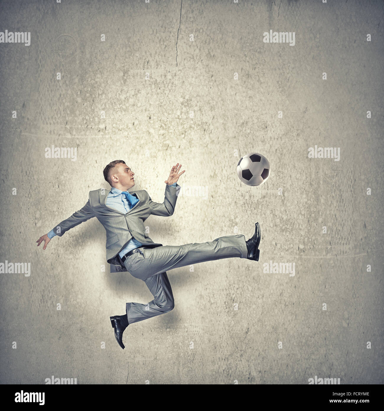 Businessman in suit jumping to hit soccer ball Stock Photo - Alamy