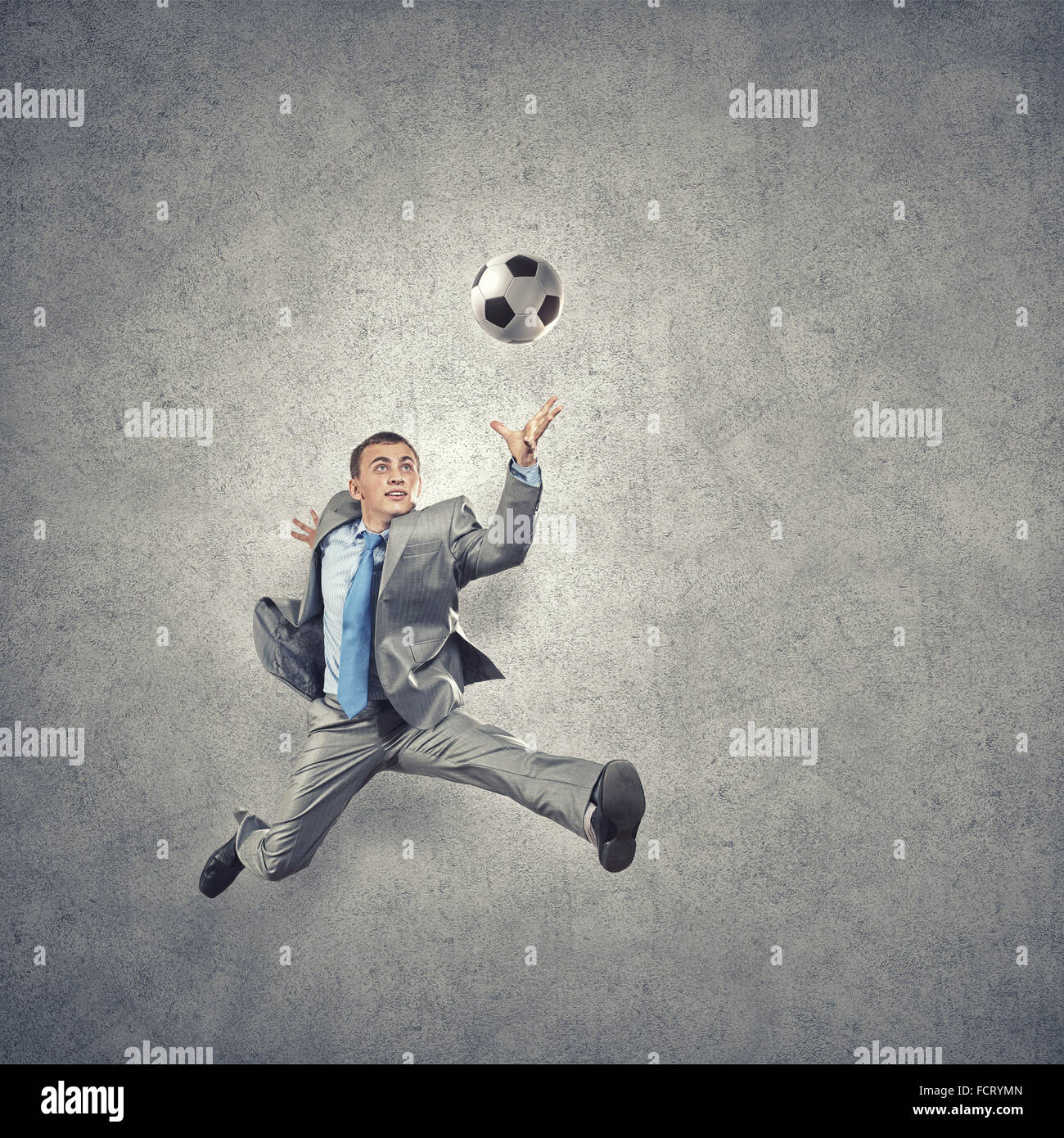 Businessman in suit jumping to hit soccer ball Stock Photo - Alamy