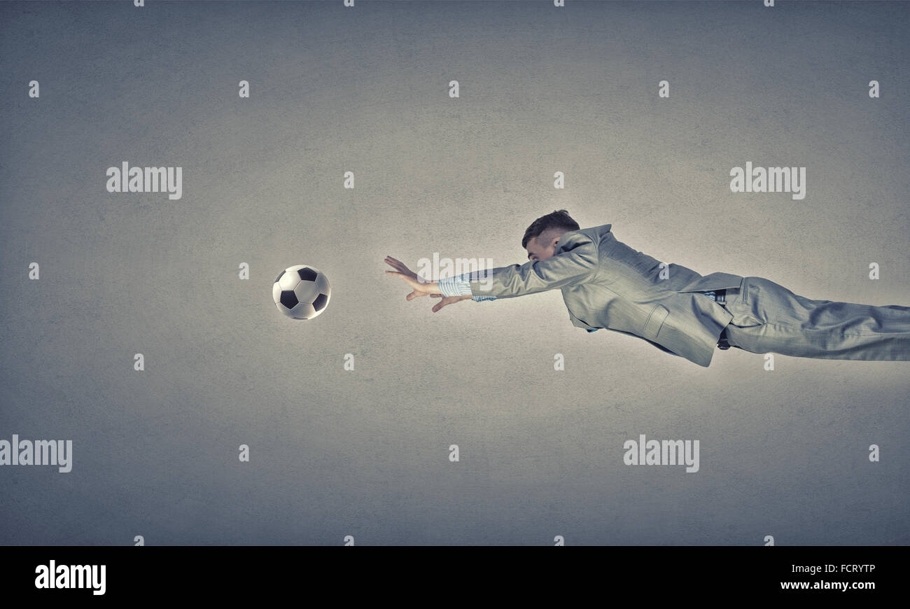 Businessman in suit jumping to hit soccer ball Stock Photo - Alamy