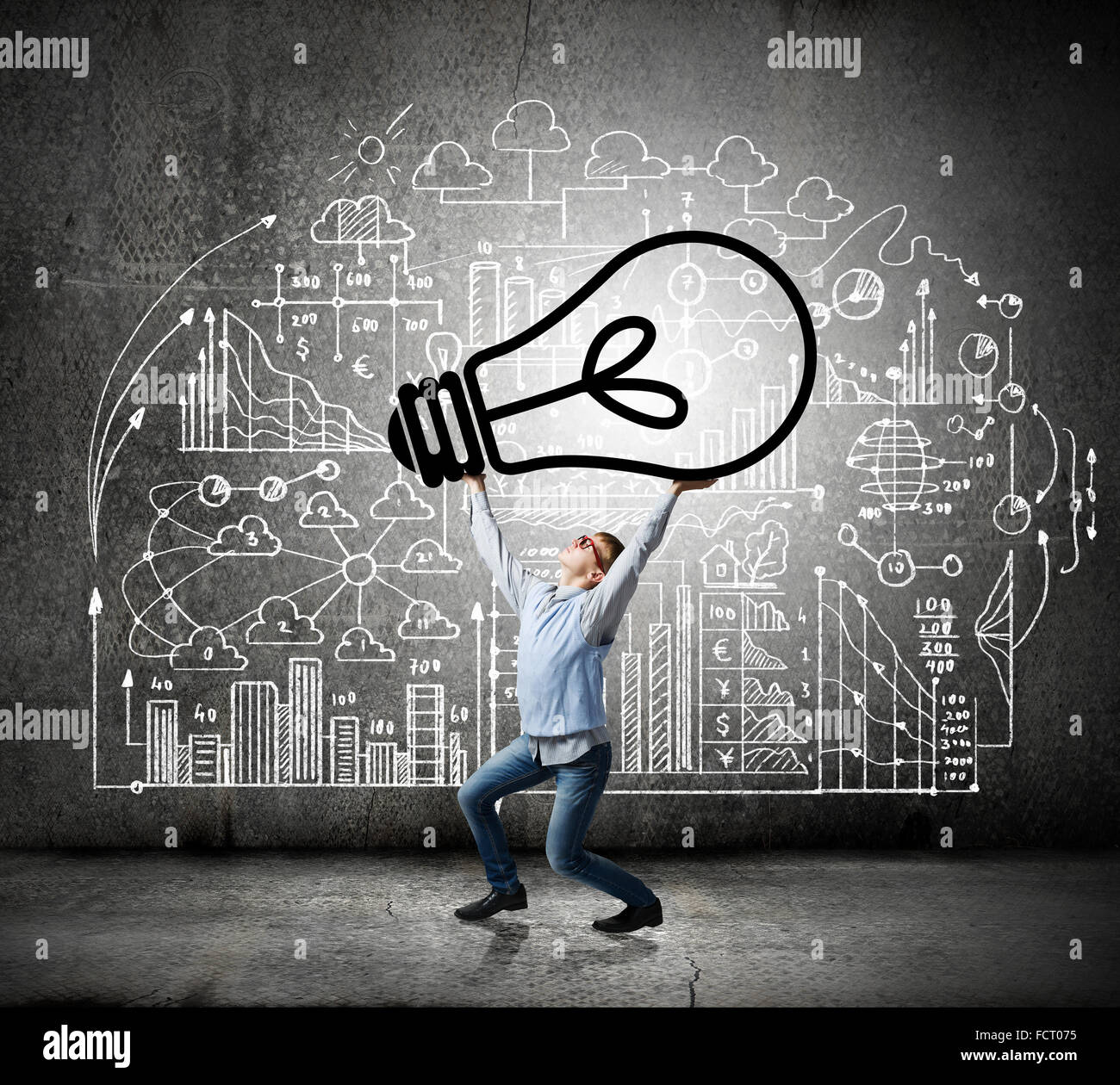 Young man lifting big bulb above head Stock Photo - Alamy