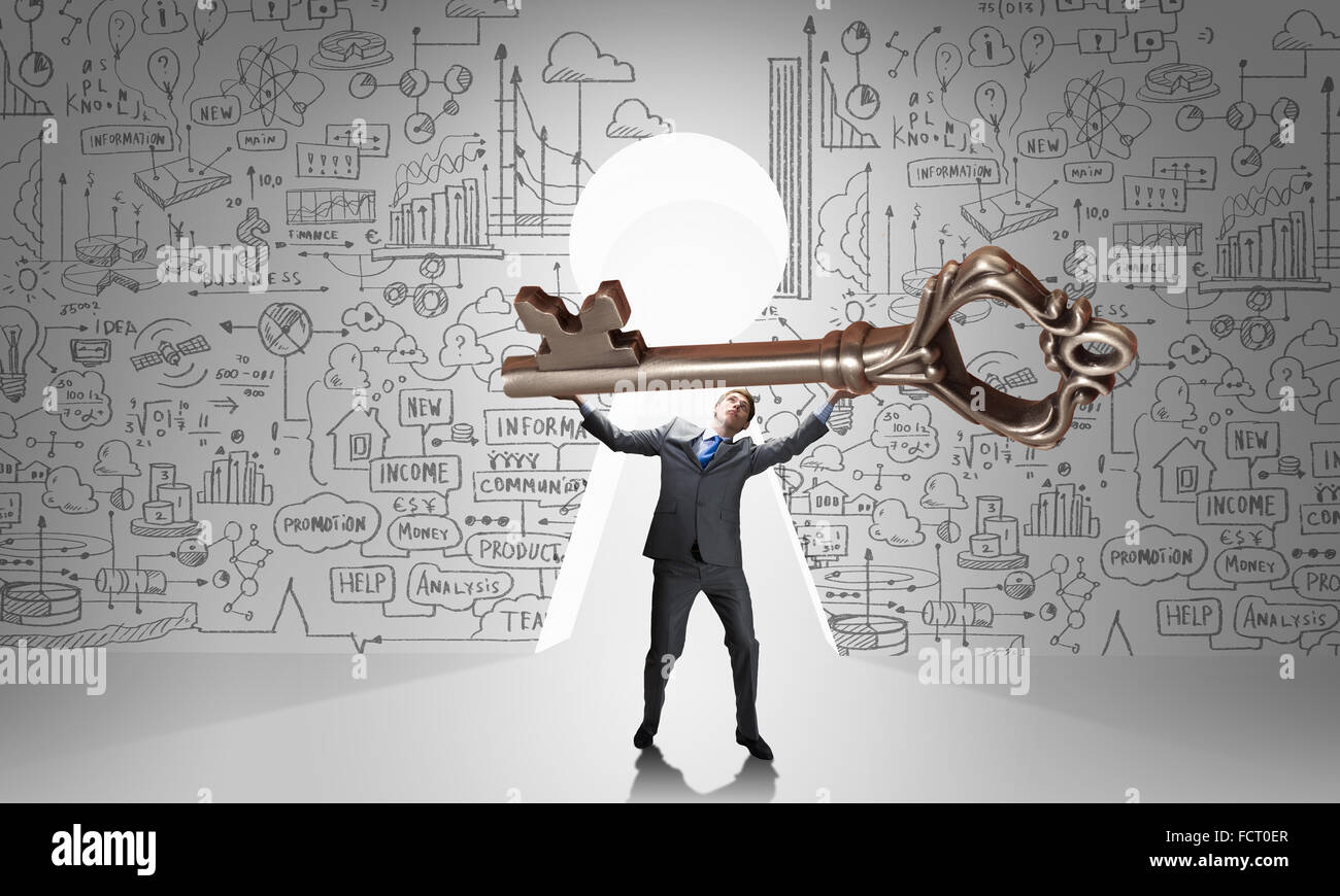 Young businessman and keyhole at background lifting big key above head ...