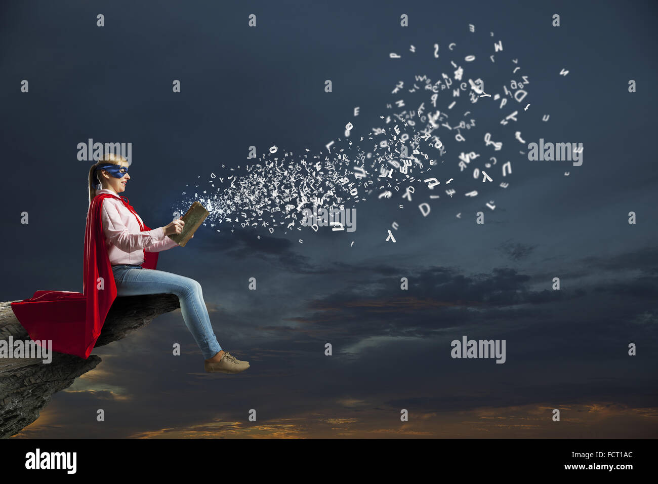 Young woman in super hero costume reading book Stock Photo - Alamy