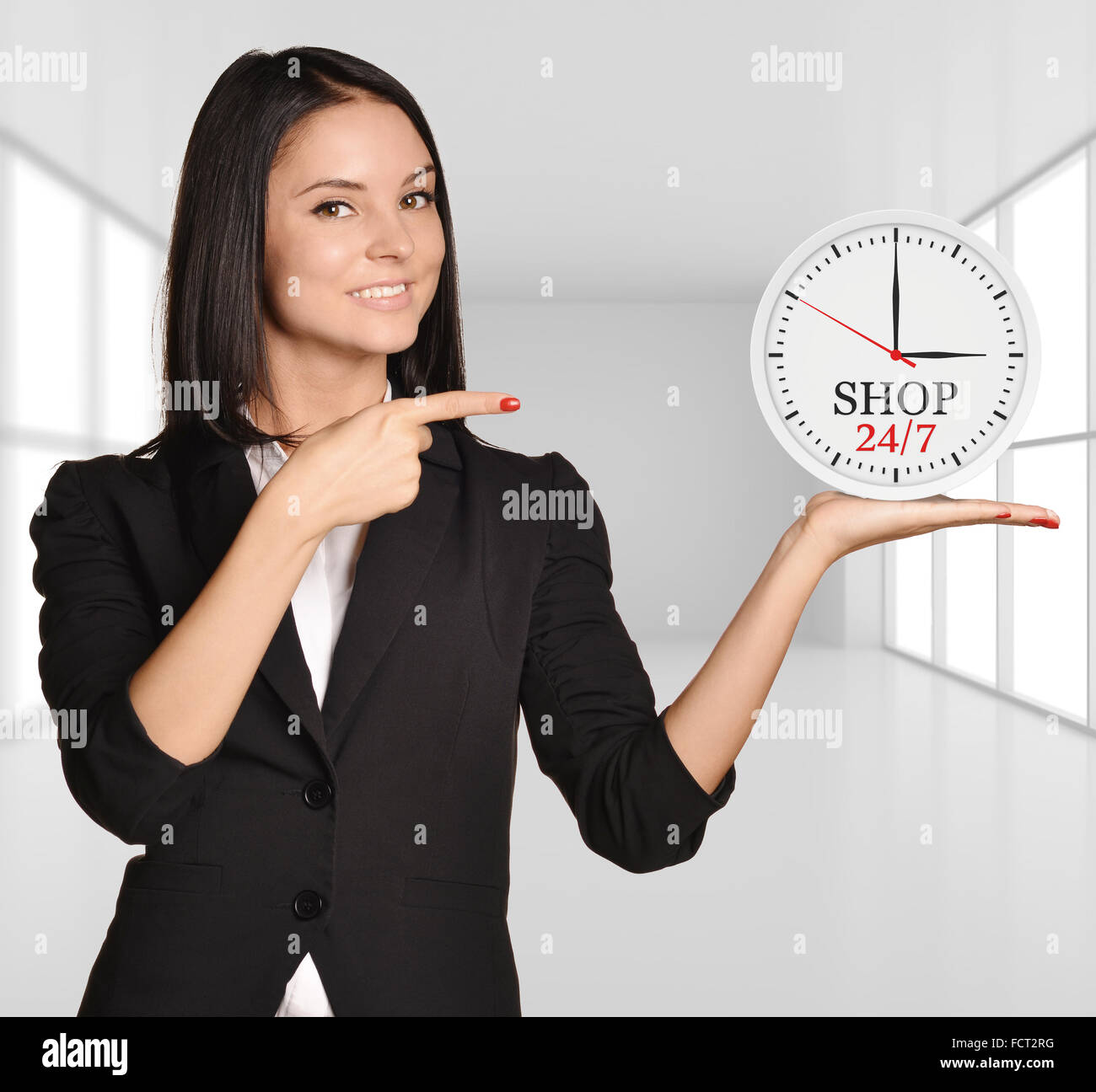 Office girl standing on background of light interior and holding clock ...