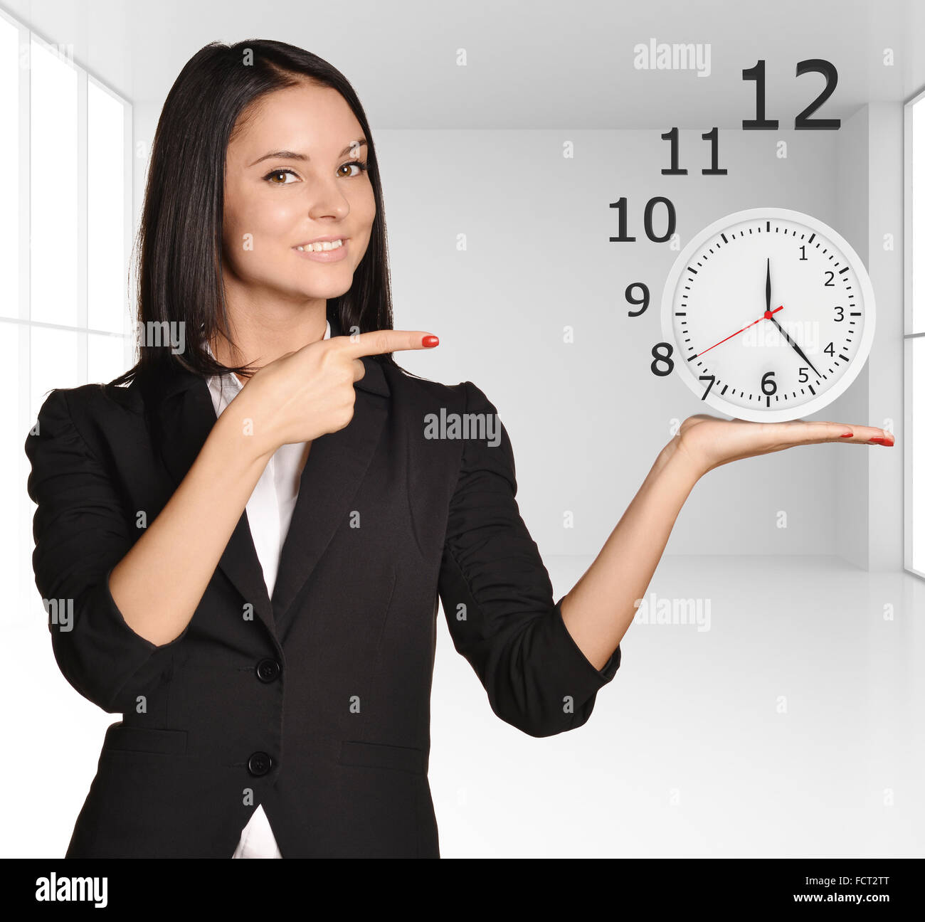 Office girl standing on background of light interior and holding clock ...