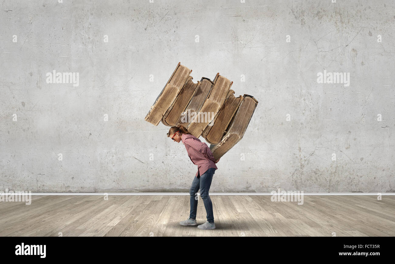 Young student girl lifting pile of old books on back Stock Photo - Alamy