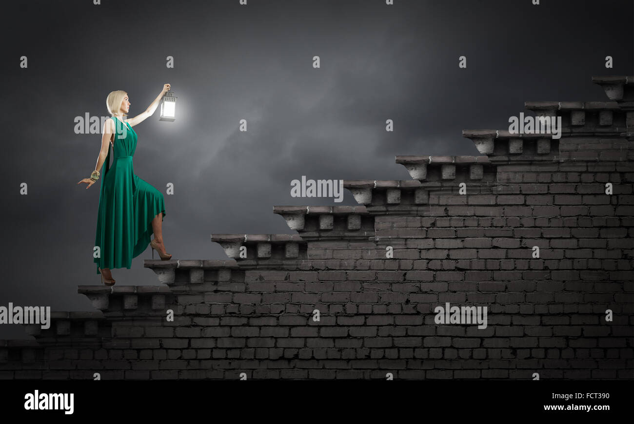 Young attractive woman in green dress with lantern walking in darkness ...