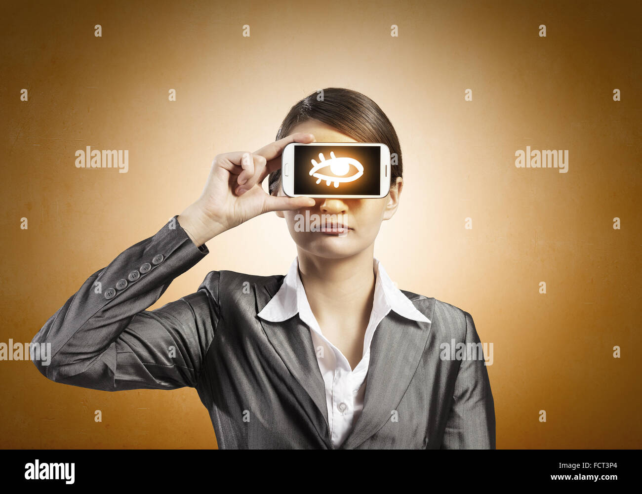 Beautiful young woman holding mobile phone against her eyes and smiling ...