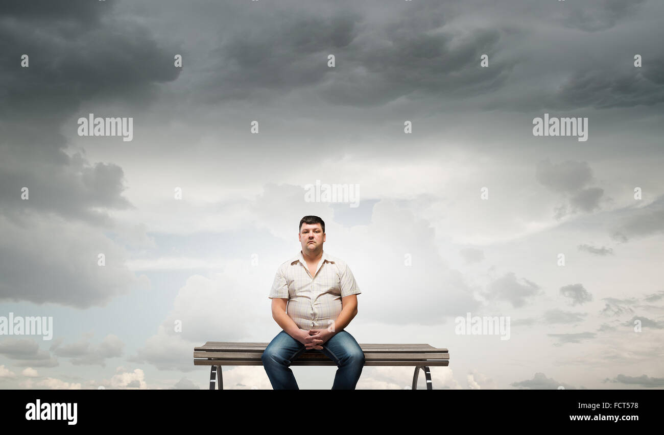 Fat man sitting on bench and looking in camera Stock Photo - Alamy
