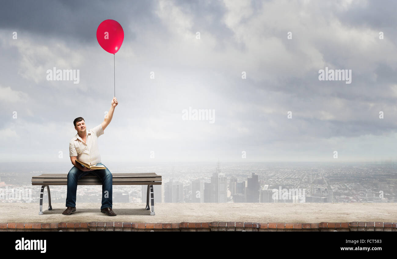 Fat man sitting on bench with book and balloon in hand Stock Photo - Alamy